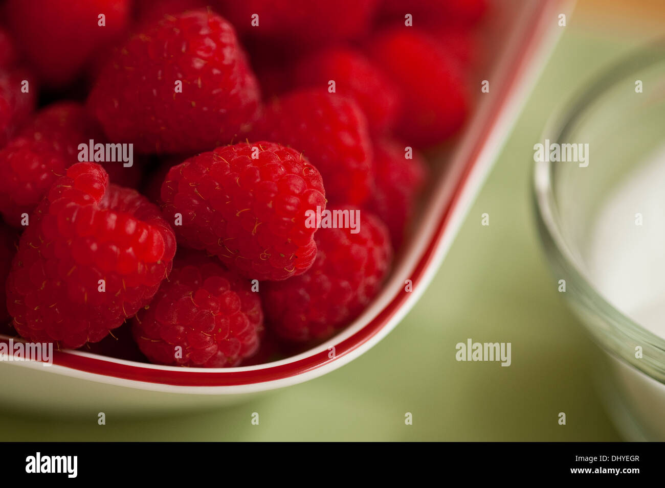 Raspberries in bowl with custard glass with sugar Stock Photo - Alamy
