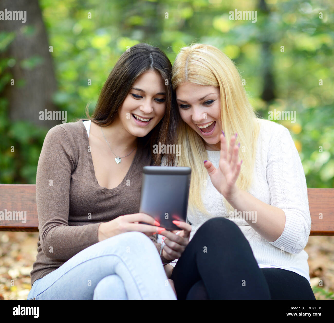 Two young women looking at tablet and chating online with friend Stock ...