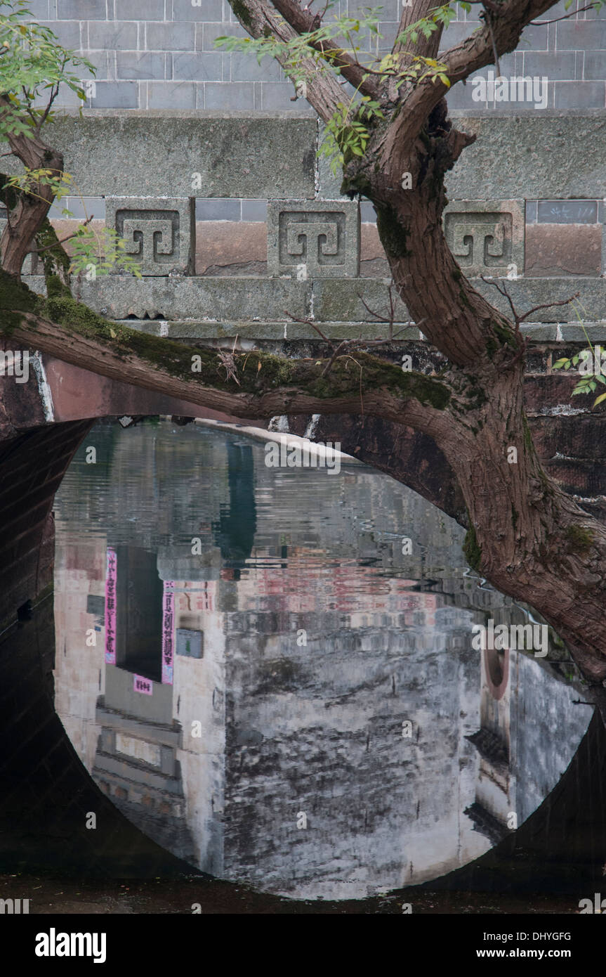 Reflections under a half-moon bridge in the heritage village of Tangmo ...