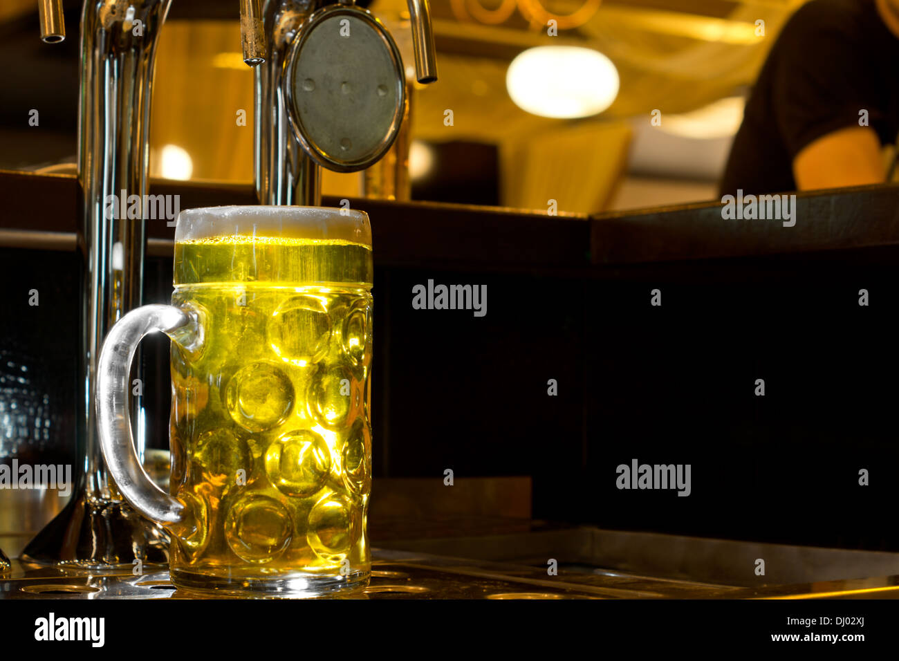 Large glowing glass tankard of golden draught beer standing on a wooden ...