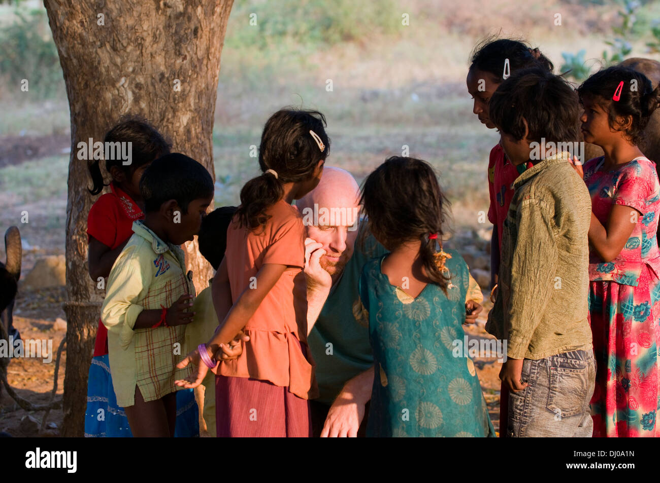 A sunlit white face crouched among a small crowd of Indian children who ...