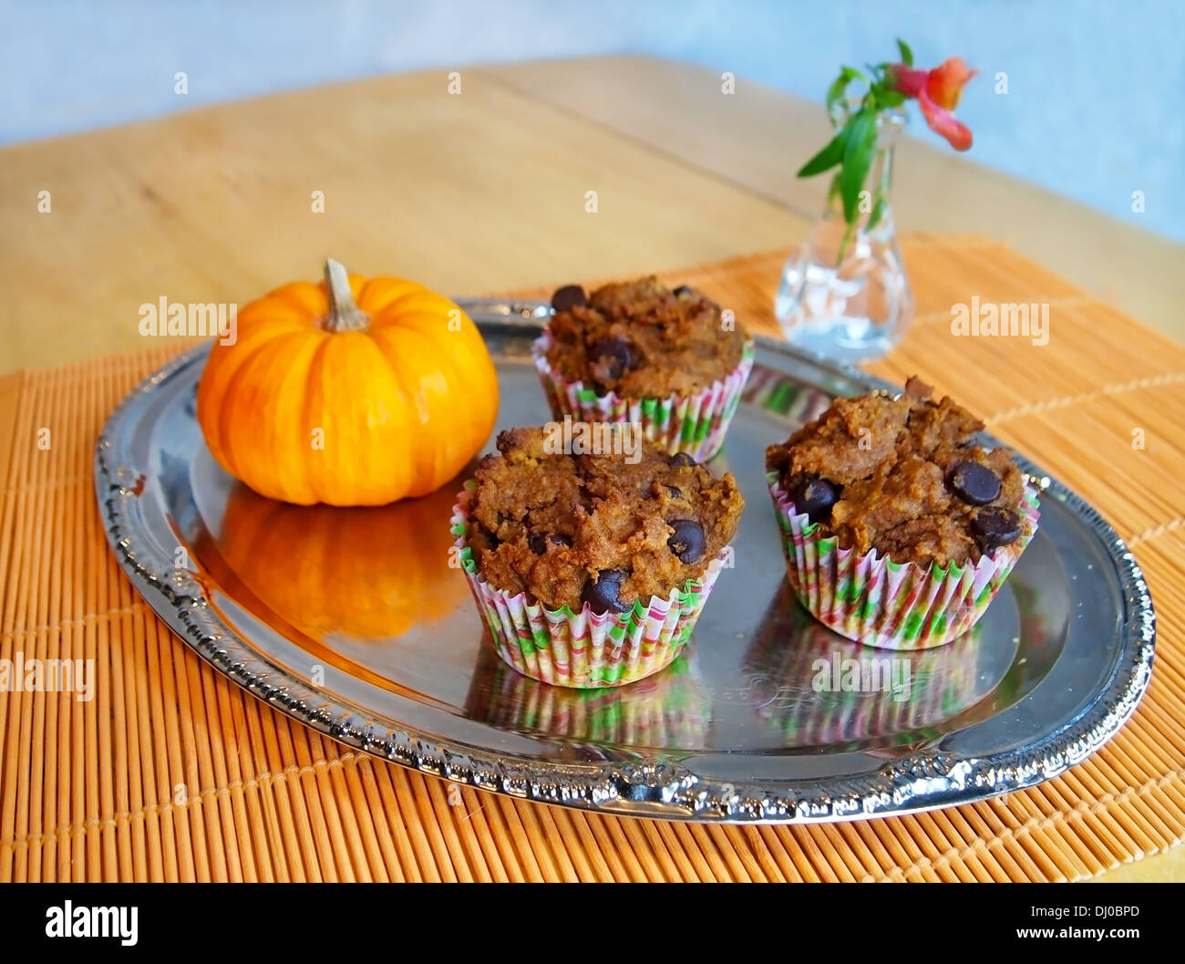 Three pumpkin chocolate chip muffins on a silver serving platter with a ...
