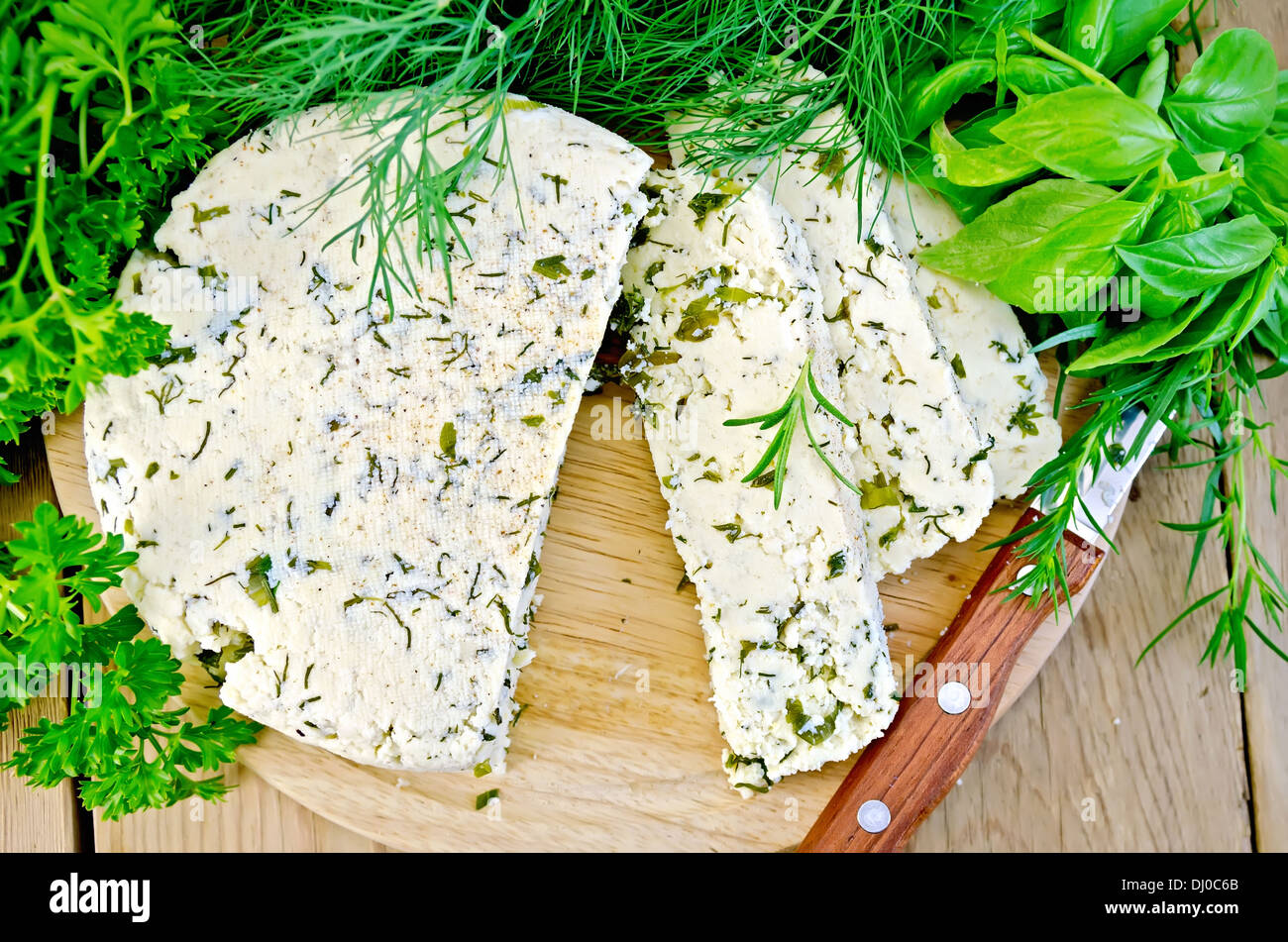 Homemade round cheese with herbs and spices cut into slices, knife on a ...