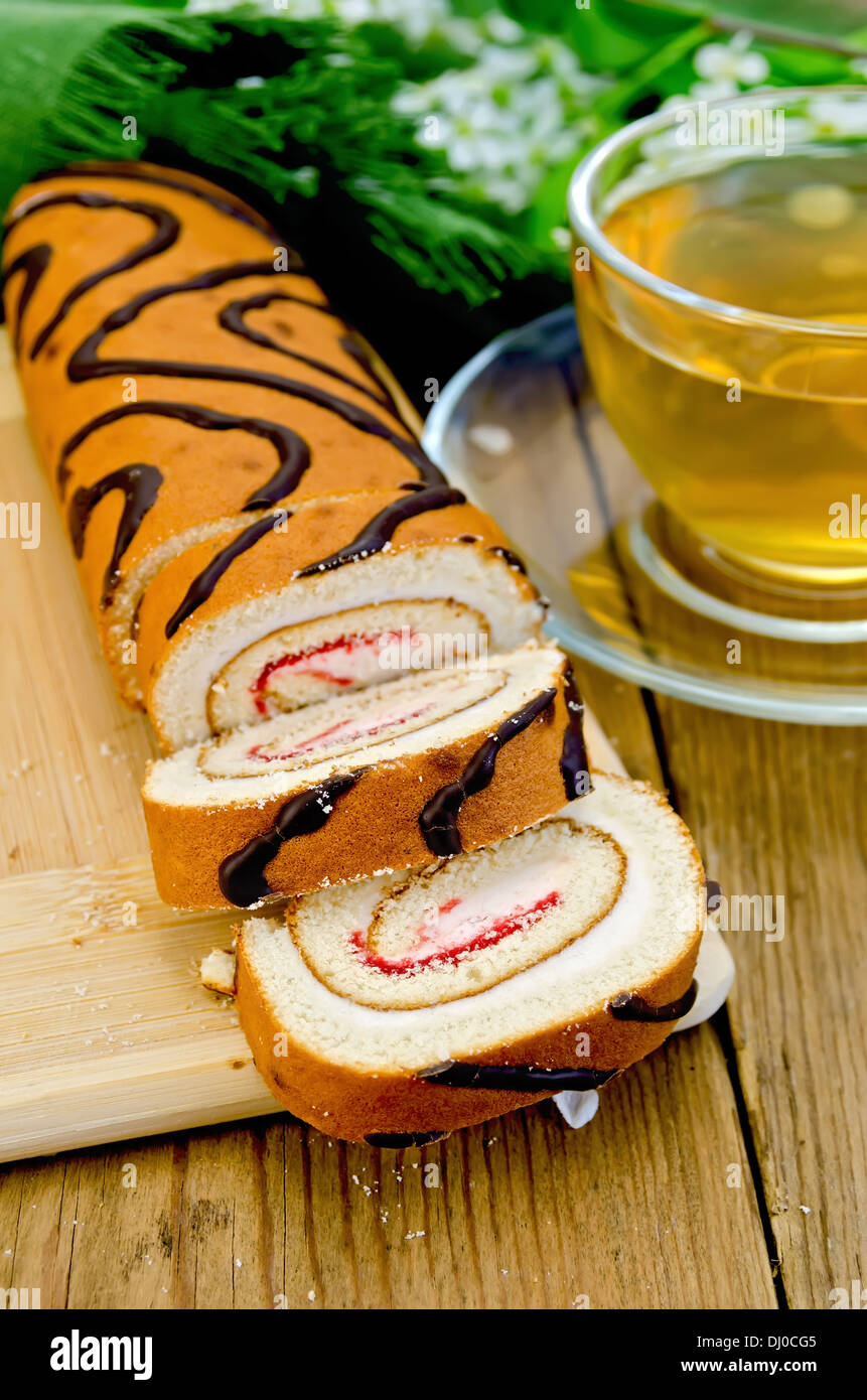 Biscuit roulade with cream and jam, a glass cup with tea, napkin ...