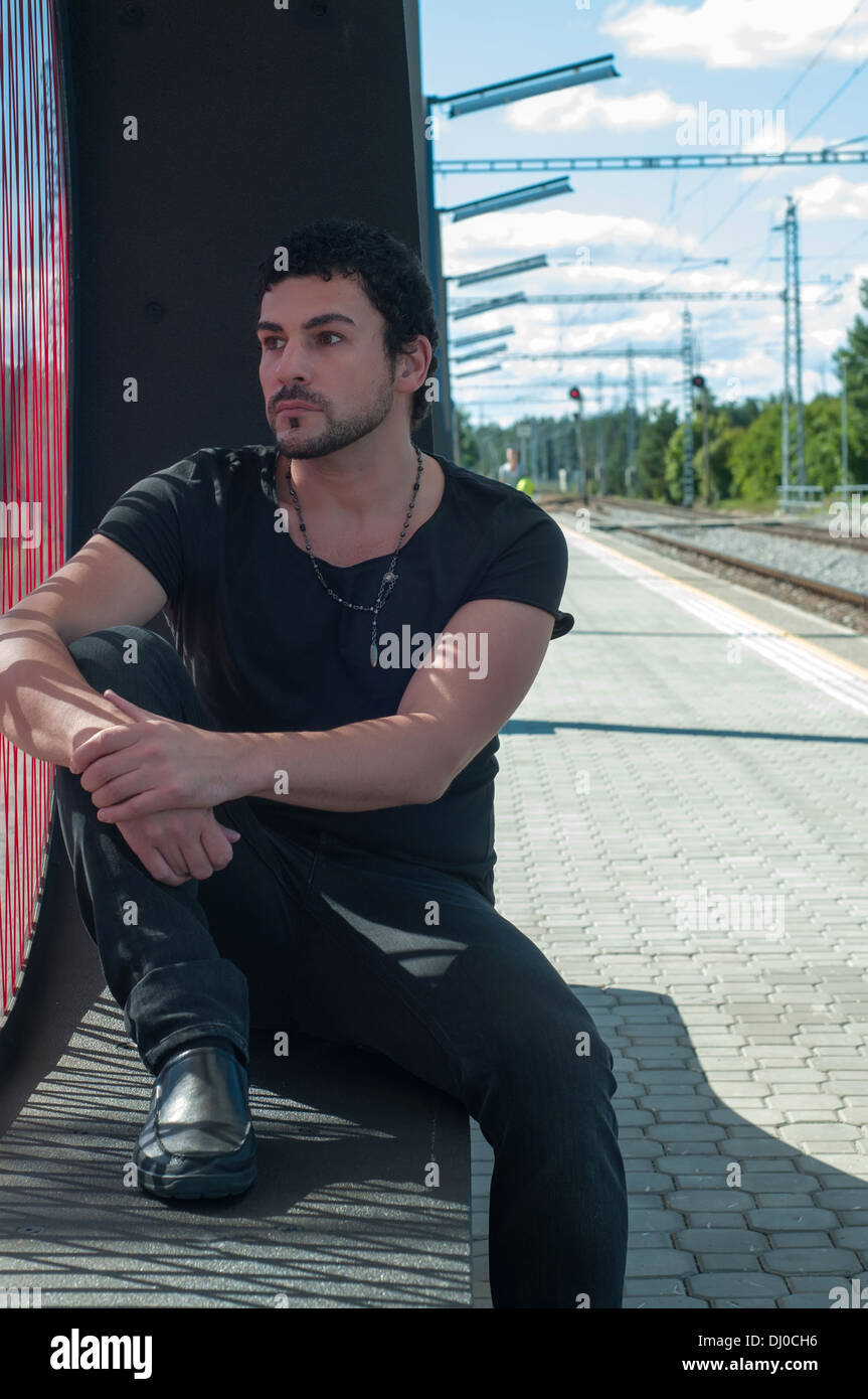 Handsome man sitting on platform Stock Photo - Alamy