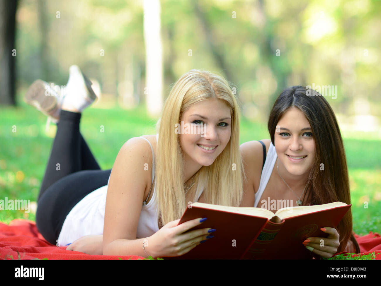Two girls reading book in park Stock Photo - Alamy