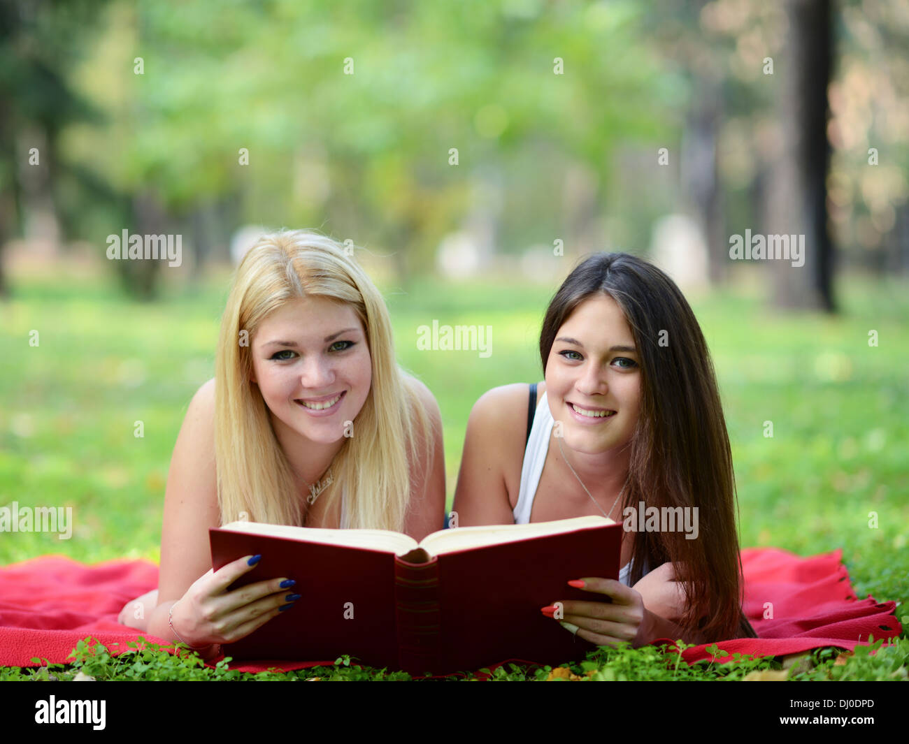 Two girls reading book in park Stock Photo - Alamy