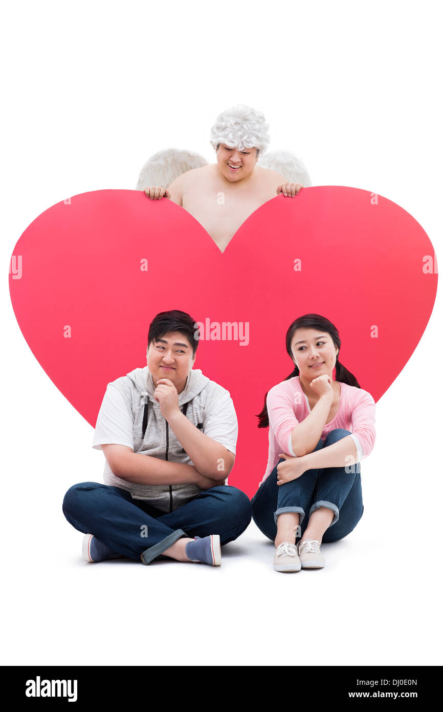 Young couple and angel with a big heart shape Stock Photo - Alamy