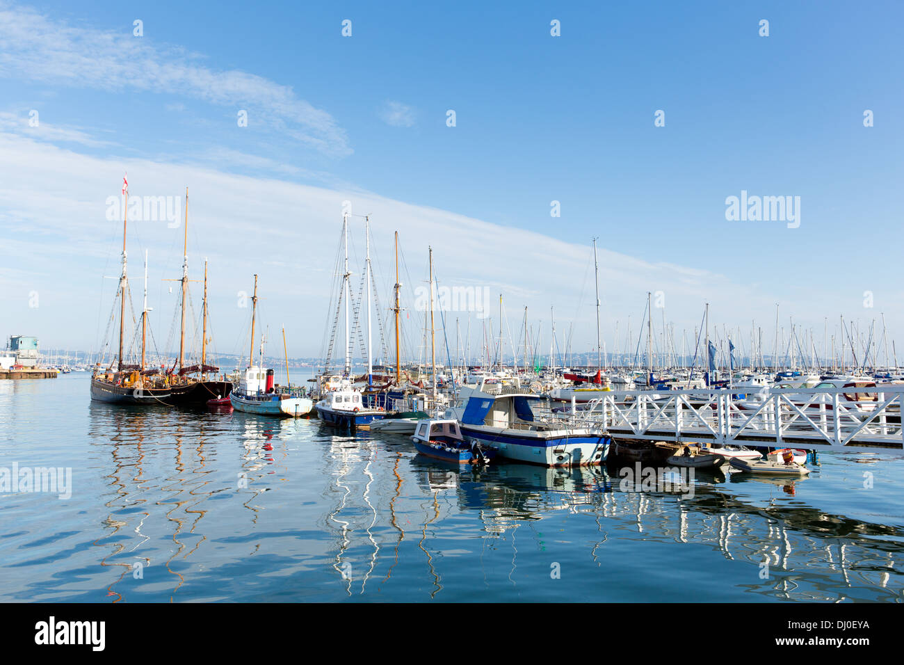 White jetty walkway leading to boats and yachts in a marina with blue ...