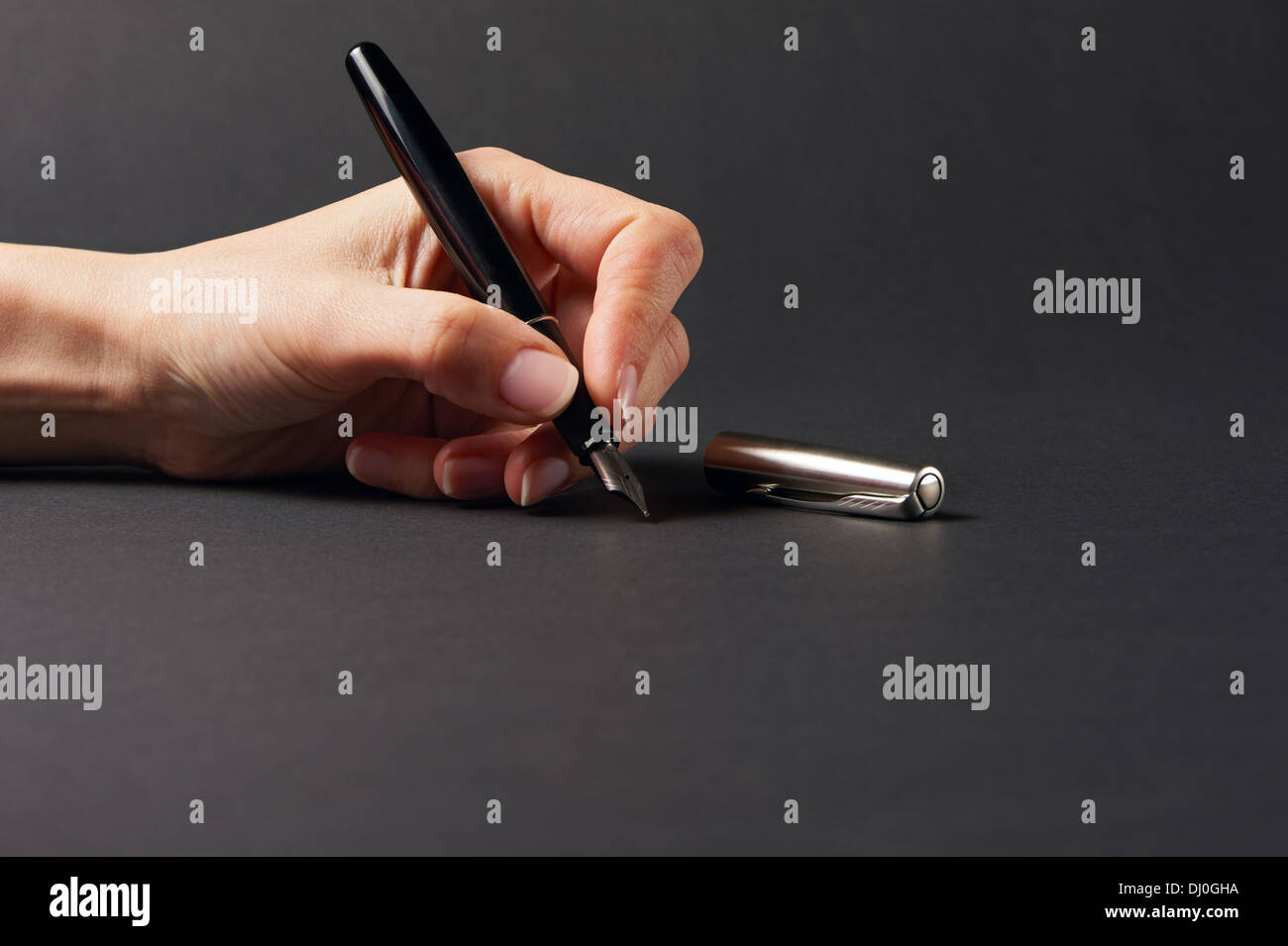 Hand with pen on black background Stock Photo - Alamy