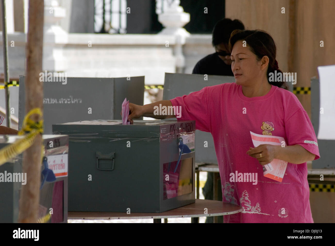 A Thai woman is putting her ballot into a ballot box during a national ...