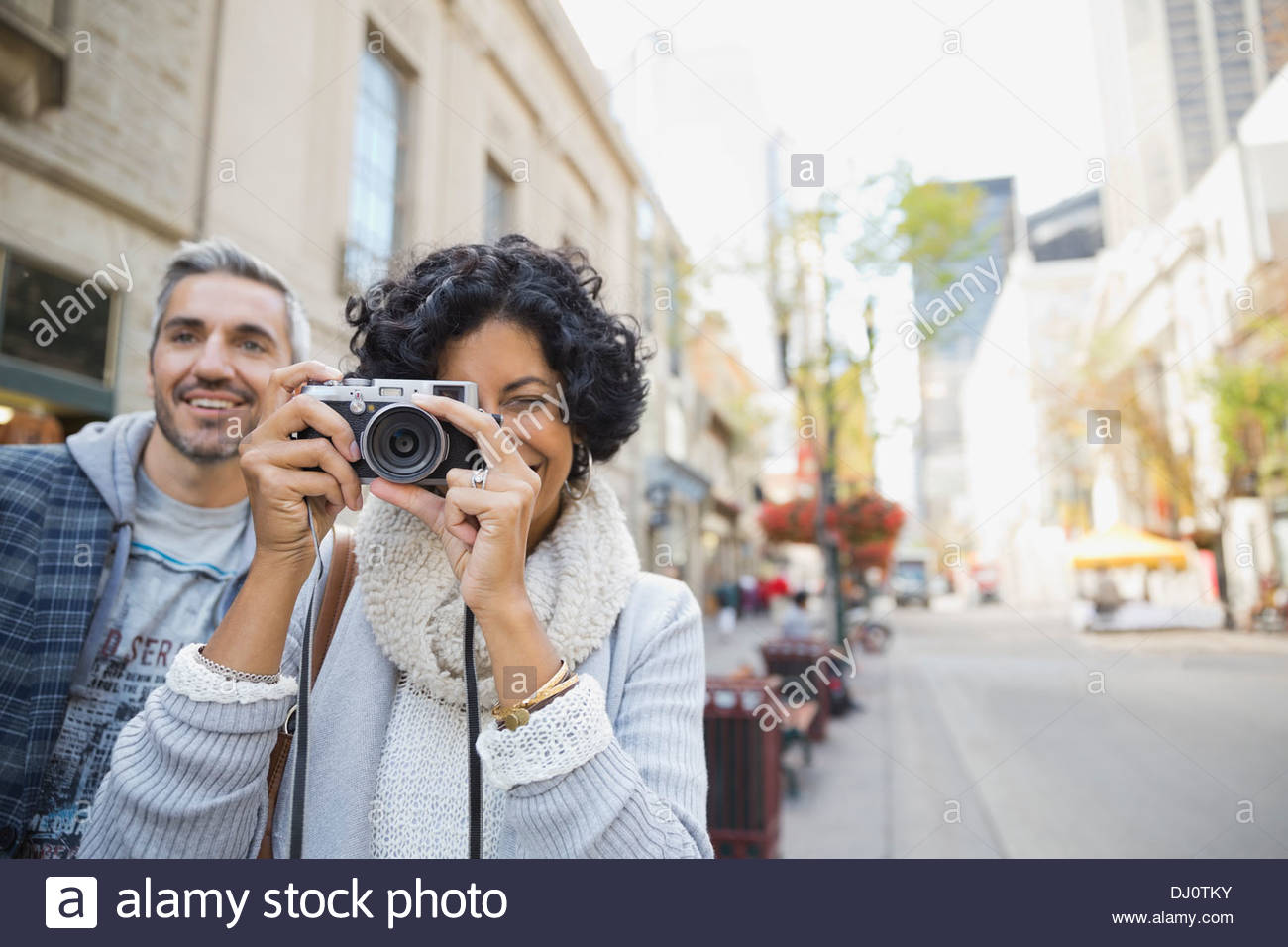 Woman photographing with man on city street Stock Photo - Alamy
