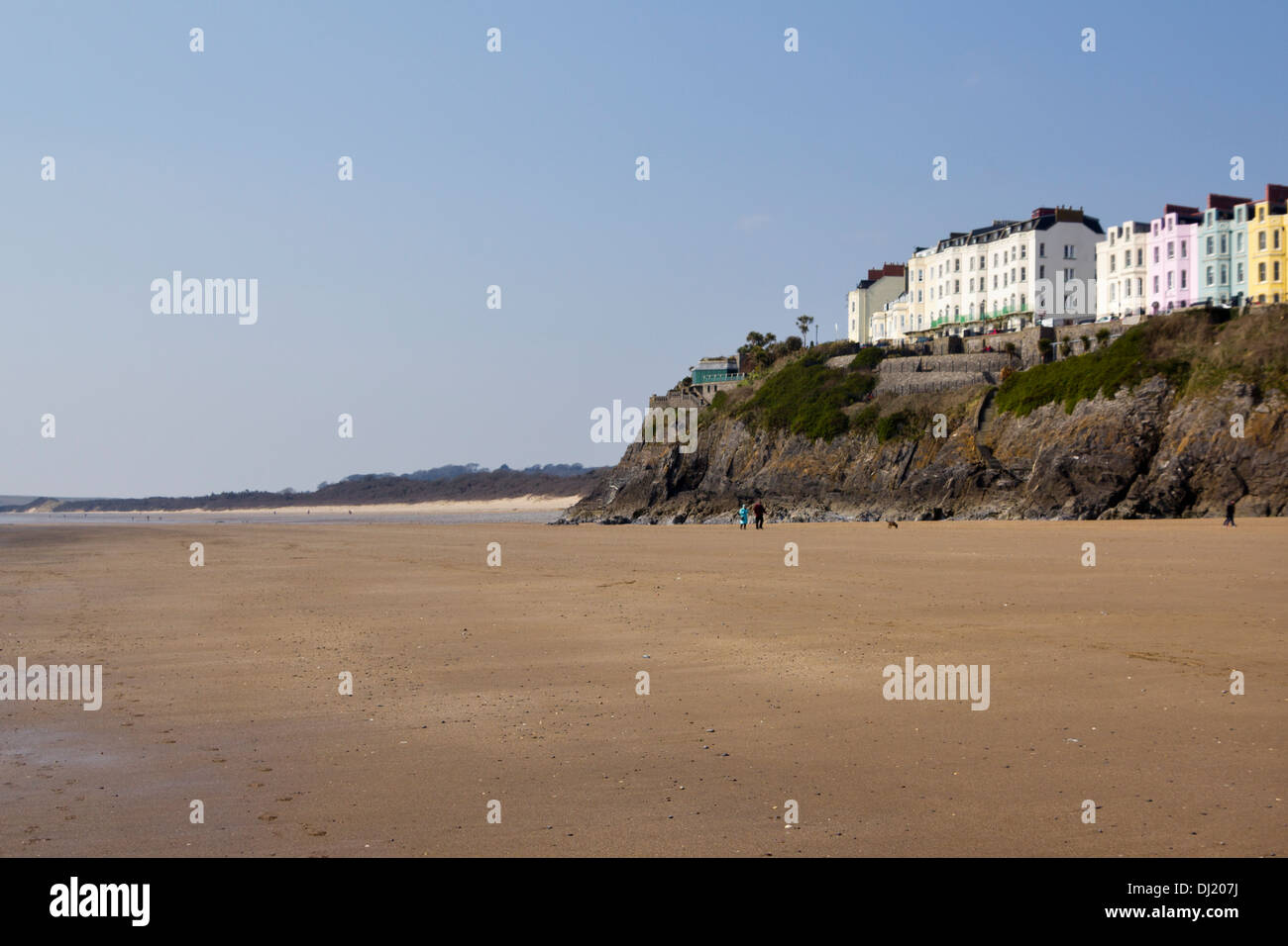 A scattering of people walking on windy Tenby South Beach in spring ...