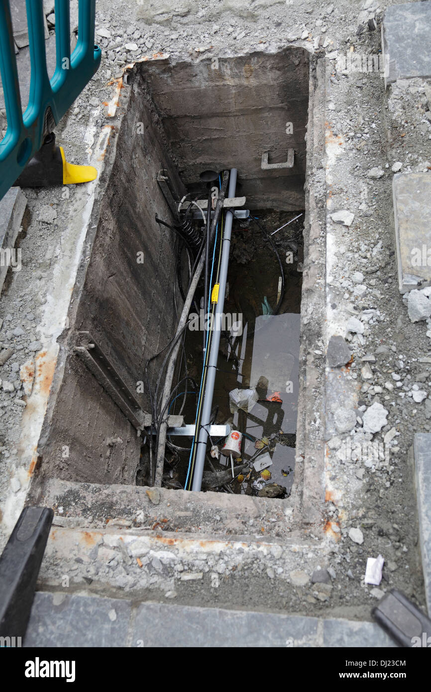 An open manhole for access to utility services on a pavement, Scotland ...