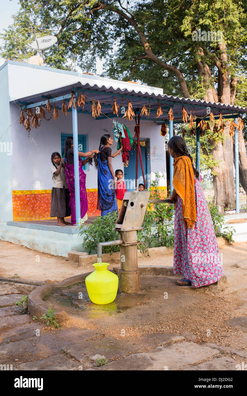 Indian woman filling plastic water pot from a rural village hand pump ...