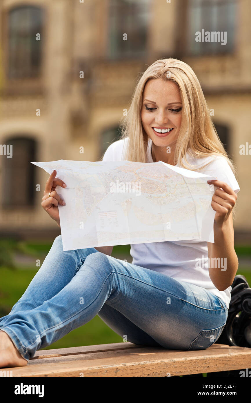 Pretty young woman looking at a map outdoors Stock Photo - Alamy