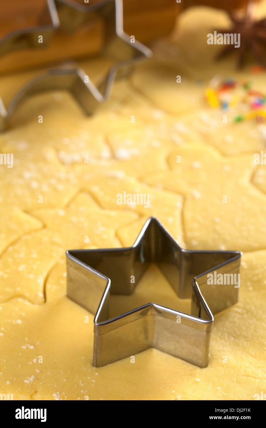 Star-shaped cookie cutter and other Christmas shapes cut into dough ...