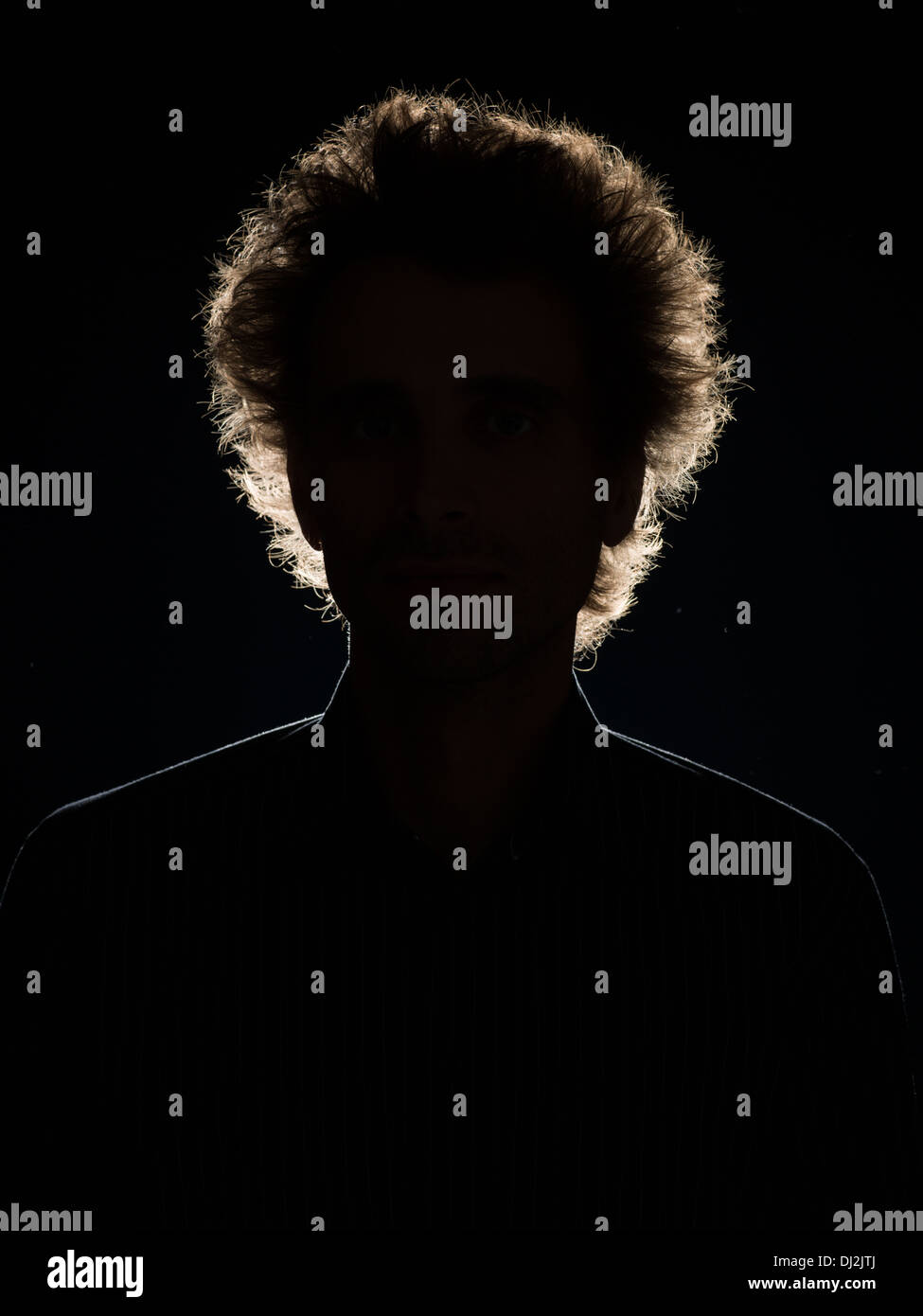 front view of man in shadow with back lighting on black background ...