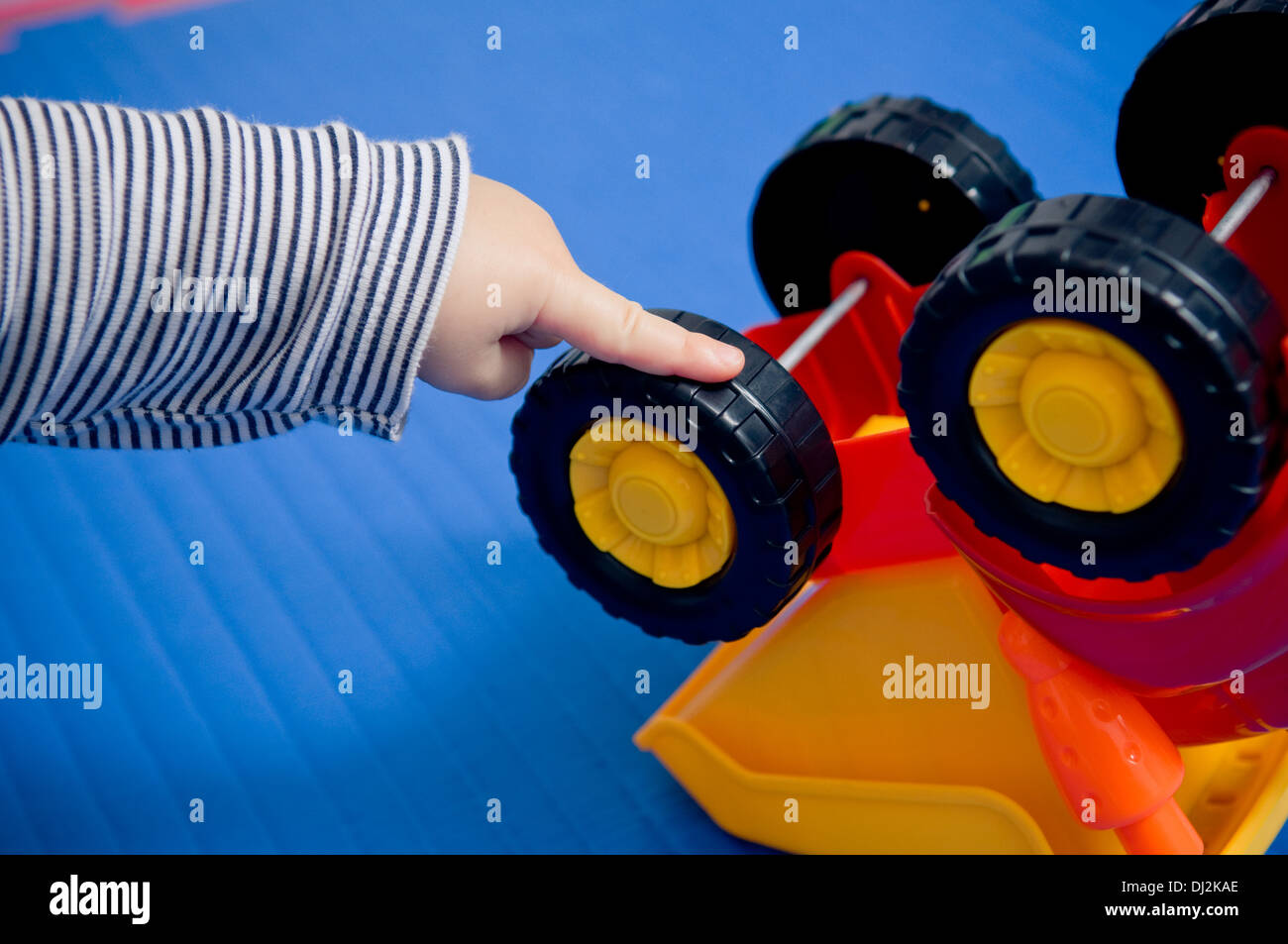 Toddler's hand turning wheels on plastic toy Stock Photo - Alamy
