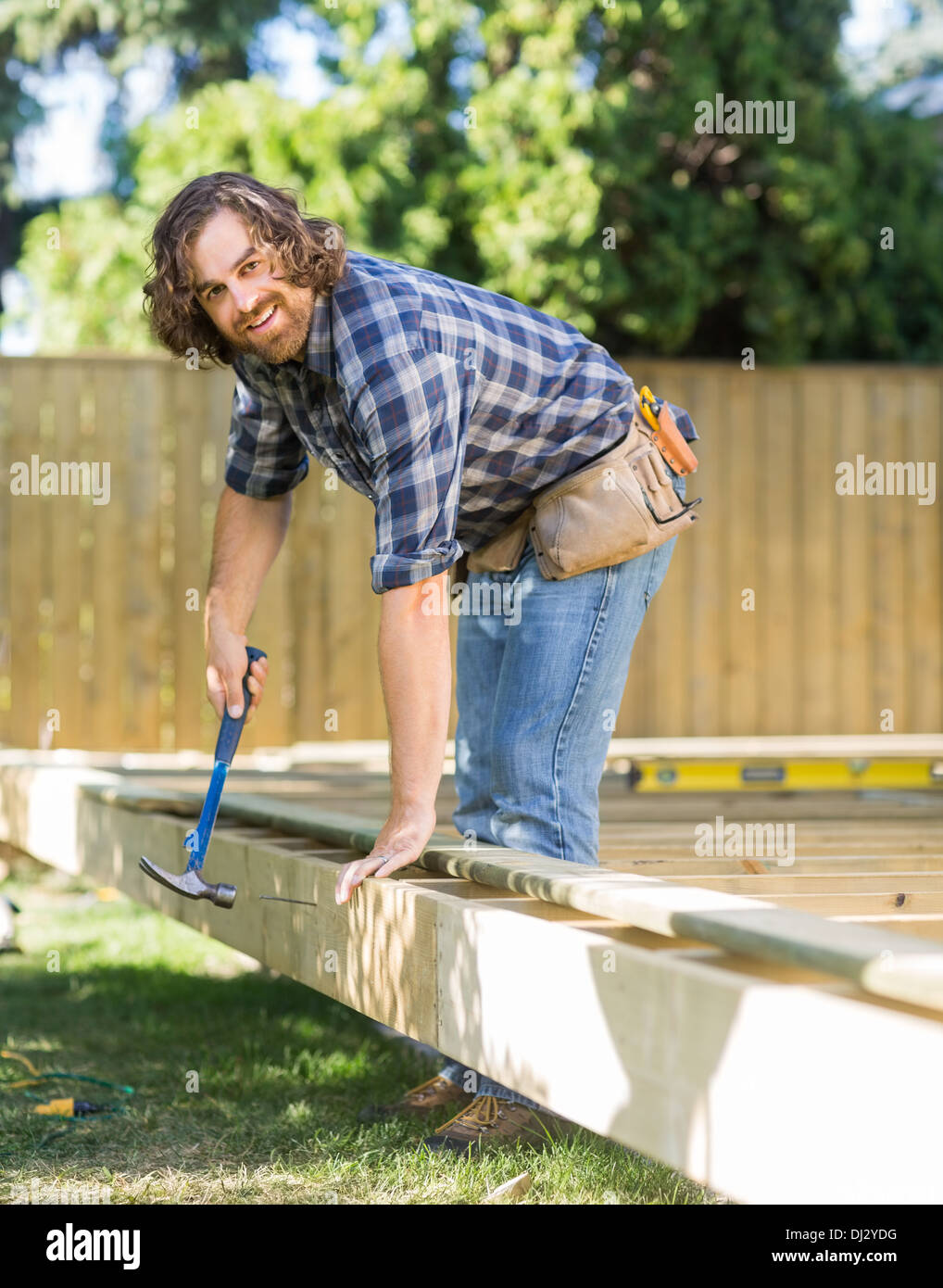Construction worker holding wooden plank and hammer hi-res stock ...