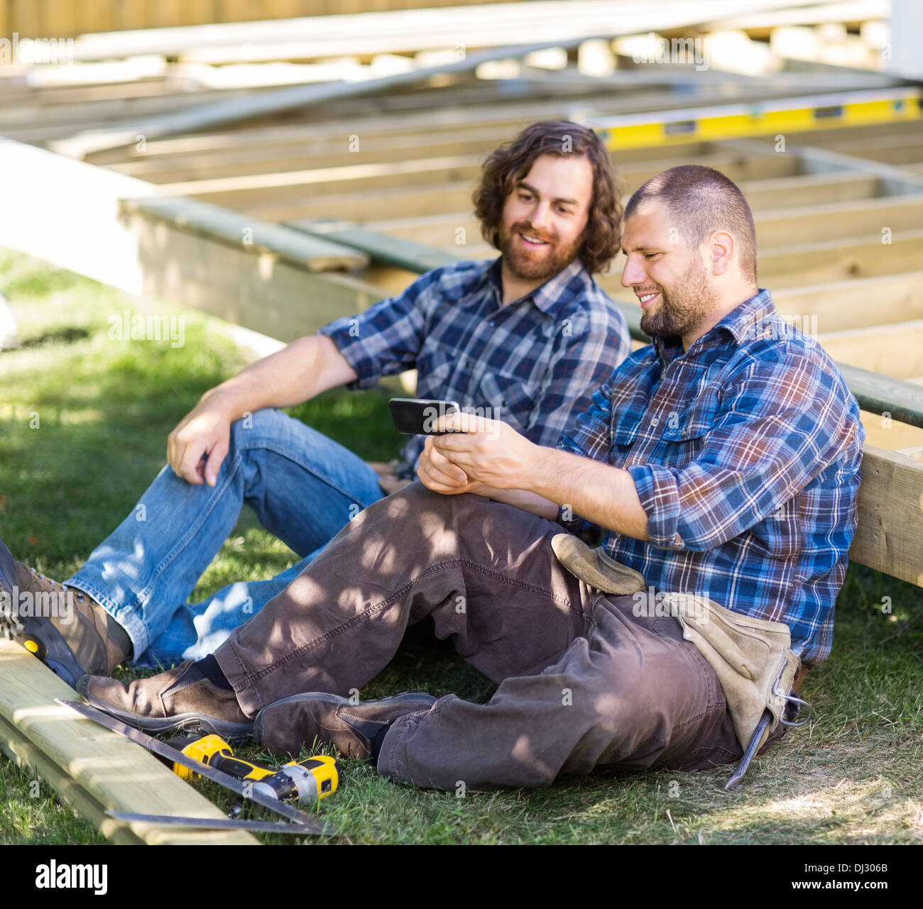 Happy Carpenters Looking At Mobile Phone At Construction Site Stock ...