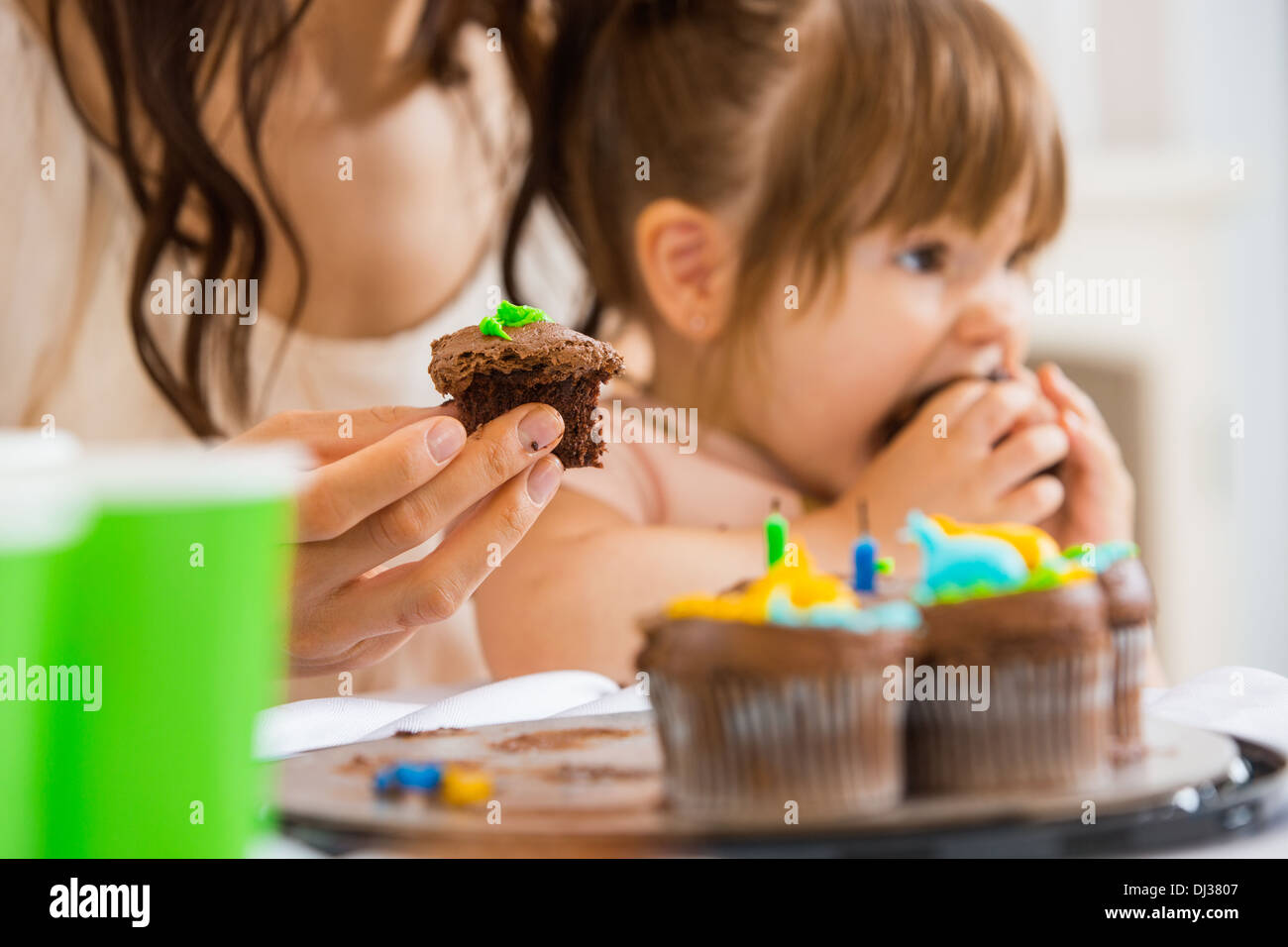 Mother Holding Cupcake With Girl Eating Cake Stock Photo - Alamy