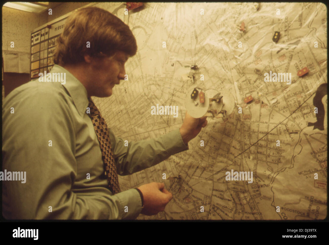 DISPATCHER MARKS LOCATIONS ON A CITY MAP FOR THE DIAL A RIDE RADIO ...