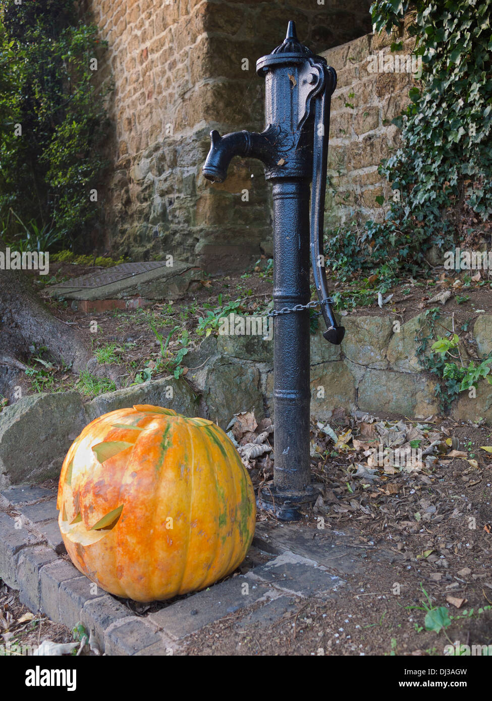 A halloween pumpkin next to a hand operated water pump Stock Photo - Alamy