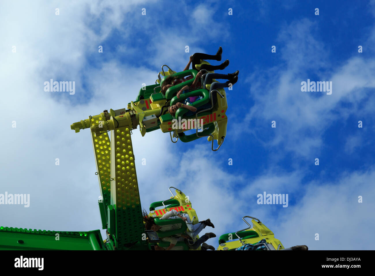 A photograph of a high spinning ride at a fun fair, against a cloudy ...