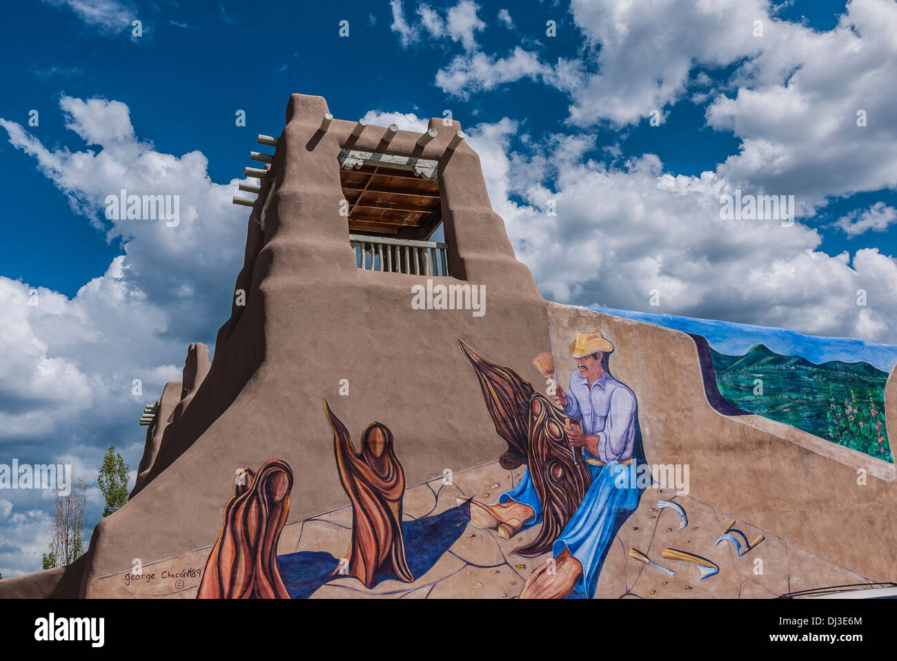 Painted mural, “El Santero,” of cowboy and indians on a two-story adobe ...