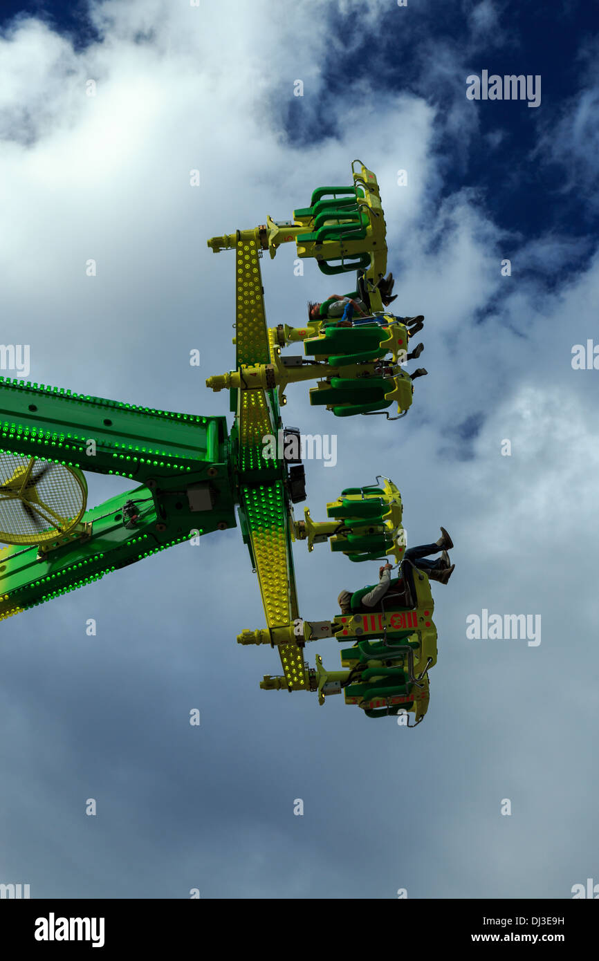 A photograph of a high spinning ride at a fun fair, against a cloudy ...