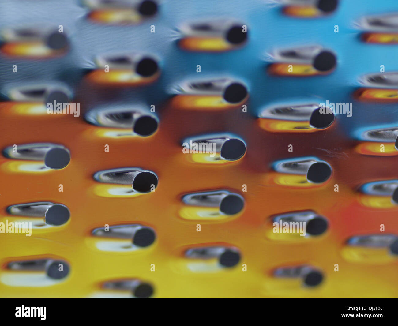 Closeup of cheese grater flutes with blue, yellow & orange coloured ...