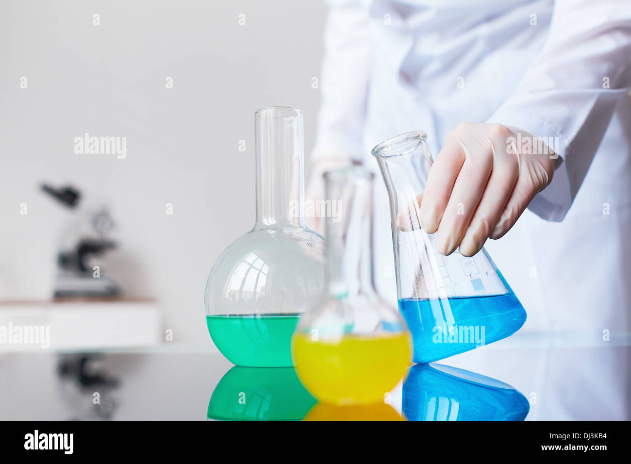 Image of glass flasks with multi-color liquids, one of the held by ...