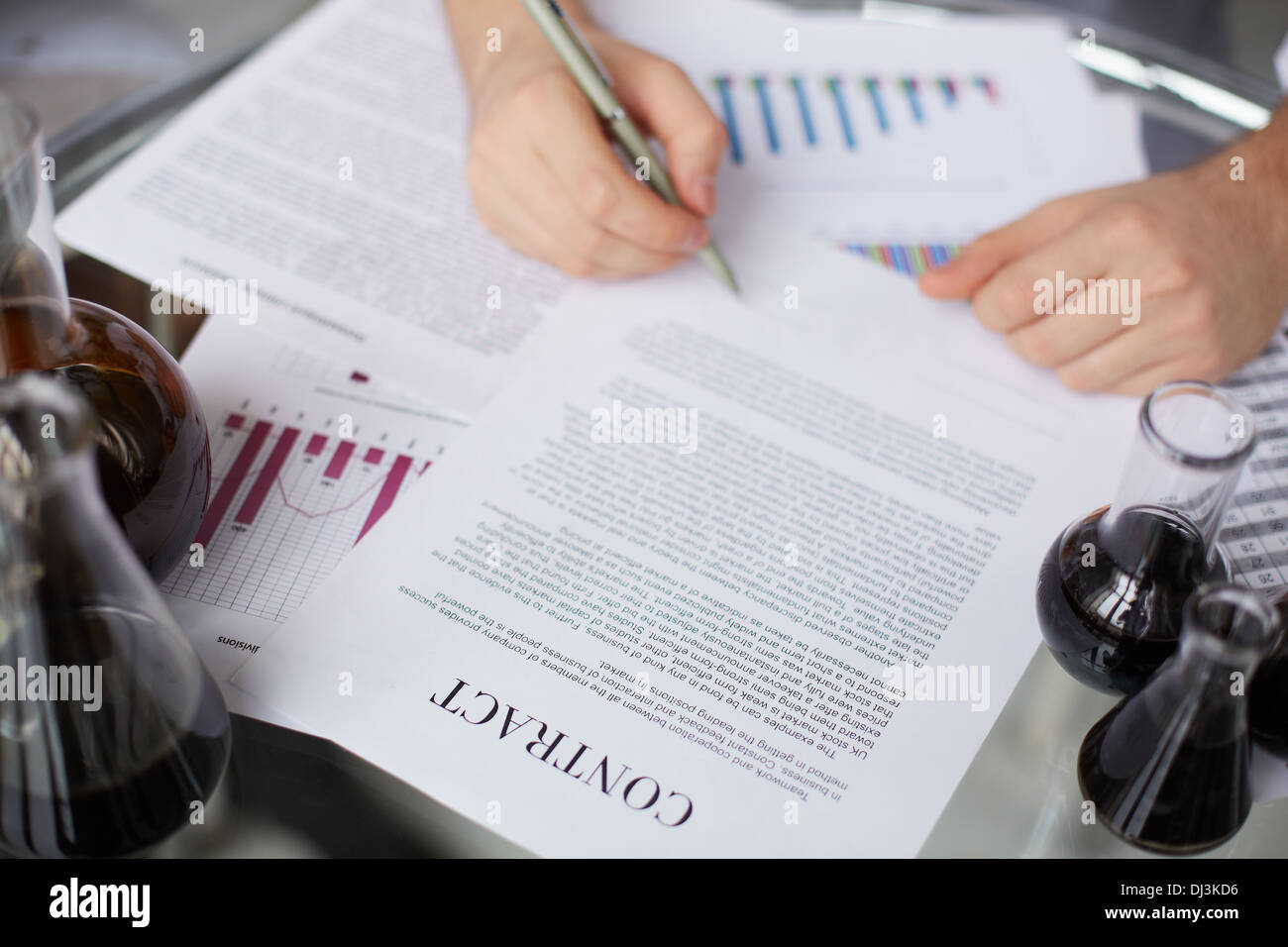 Test-tubes with liquid oil and paper agreement being signed by human ...