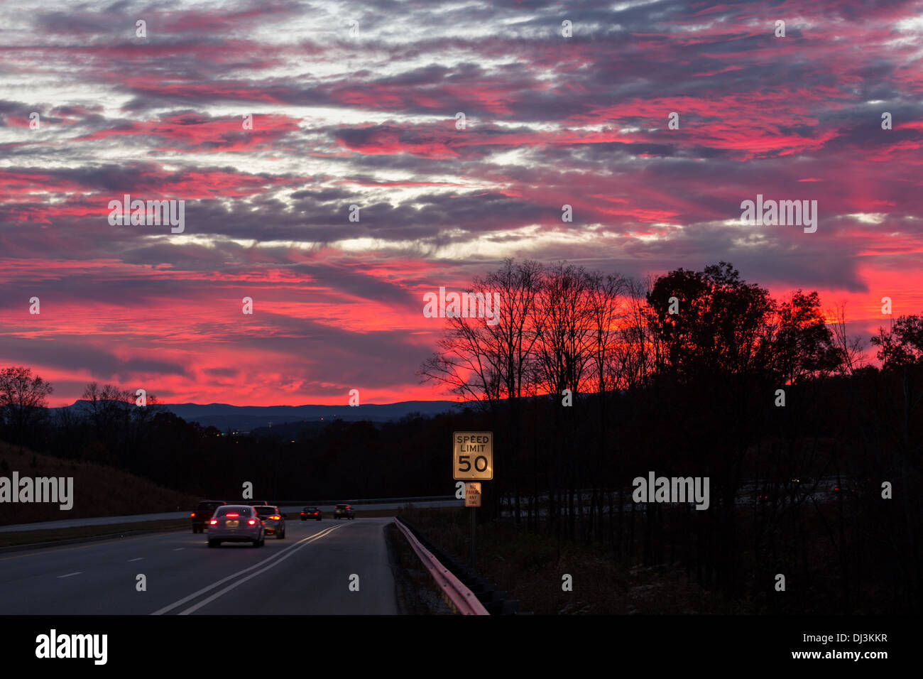 Red sunset in a partly cloudy sky, silhouetting trees Stock Photo - Alamy