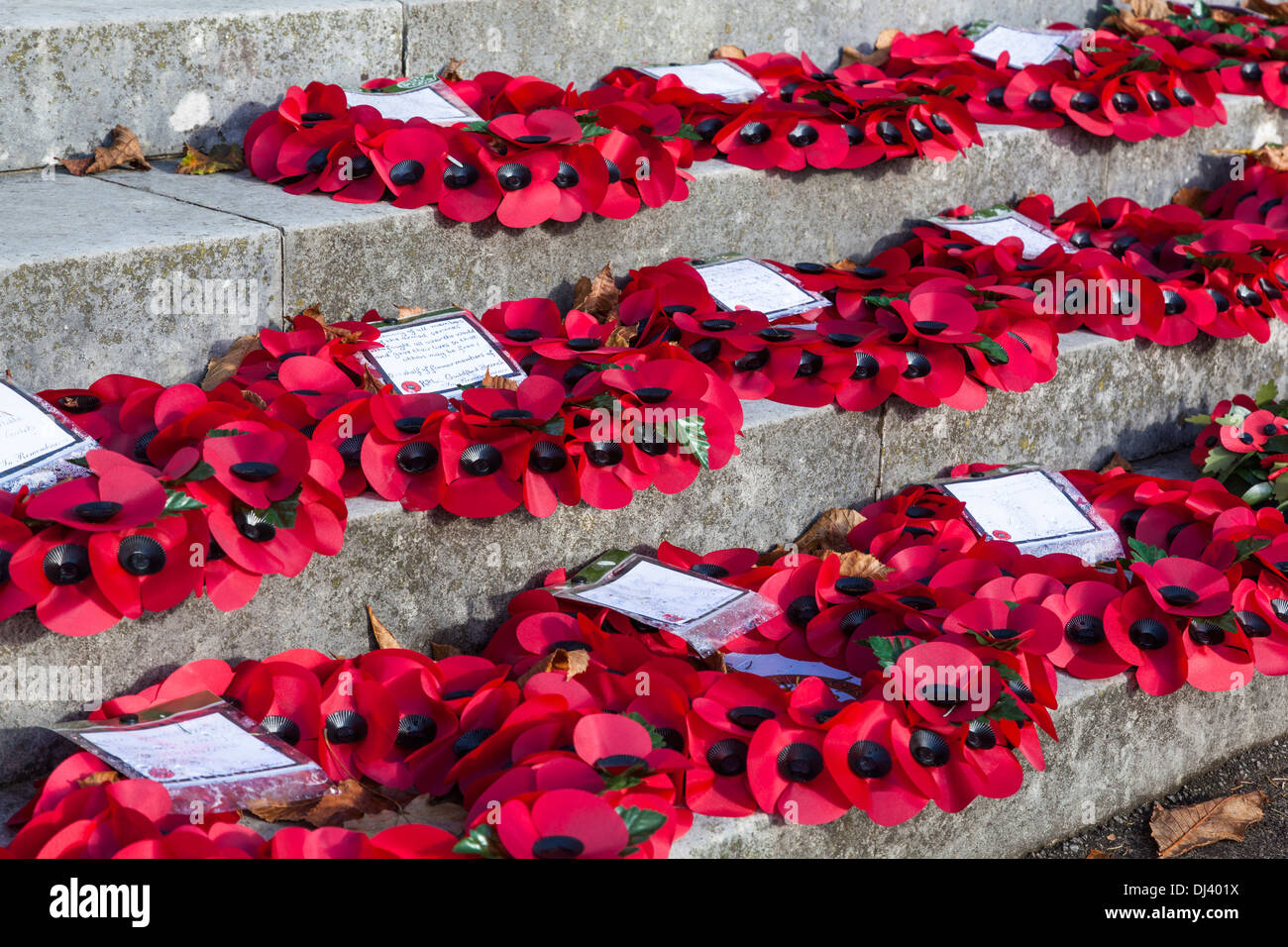 Remembrance Day poppies and wreathes laid on steps by a war memorial ...