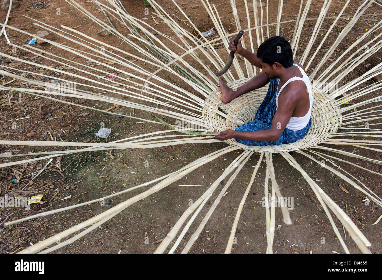 Indian man weaving a traditional goat pen from bamboo in a rural Indian ...