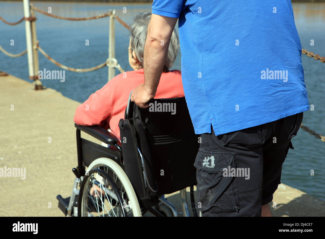 Man pushing an elderly lady in a wheelchair Stock Photo - Alamy
