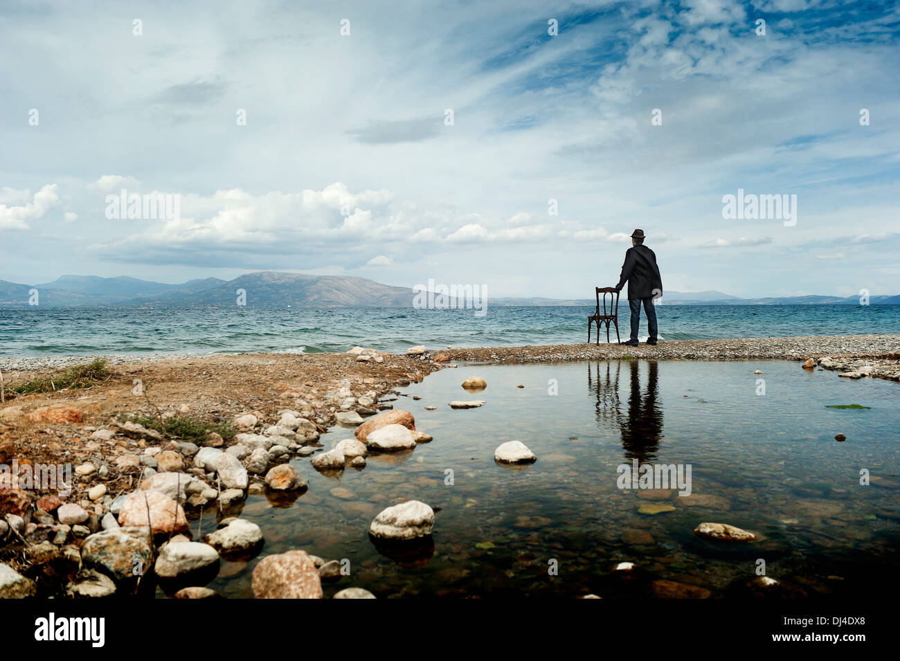 Man standing next to a chair outdoors Stock Photo - Alamy