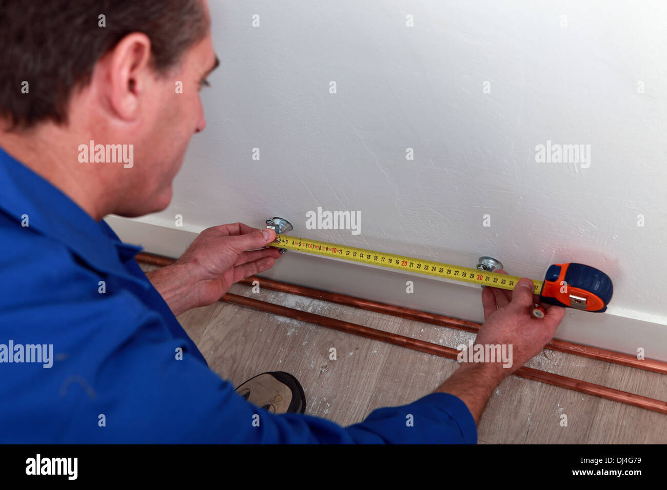 Plumber measuring length of copper pipe Stock Photo - Alamy