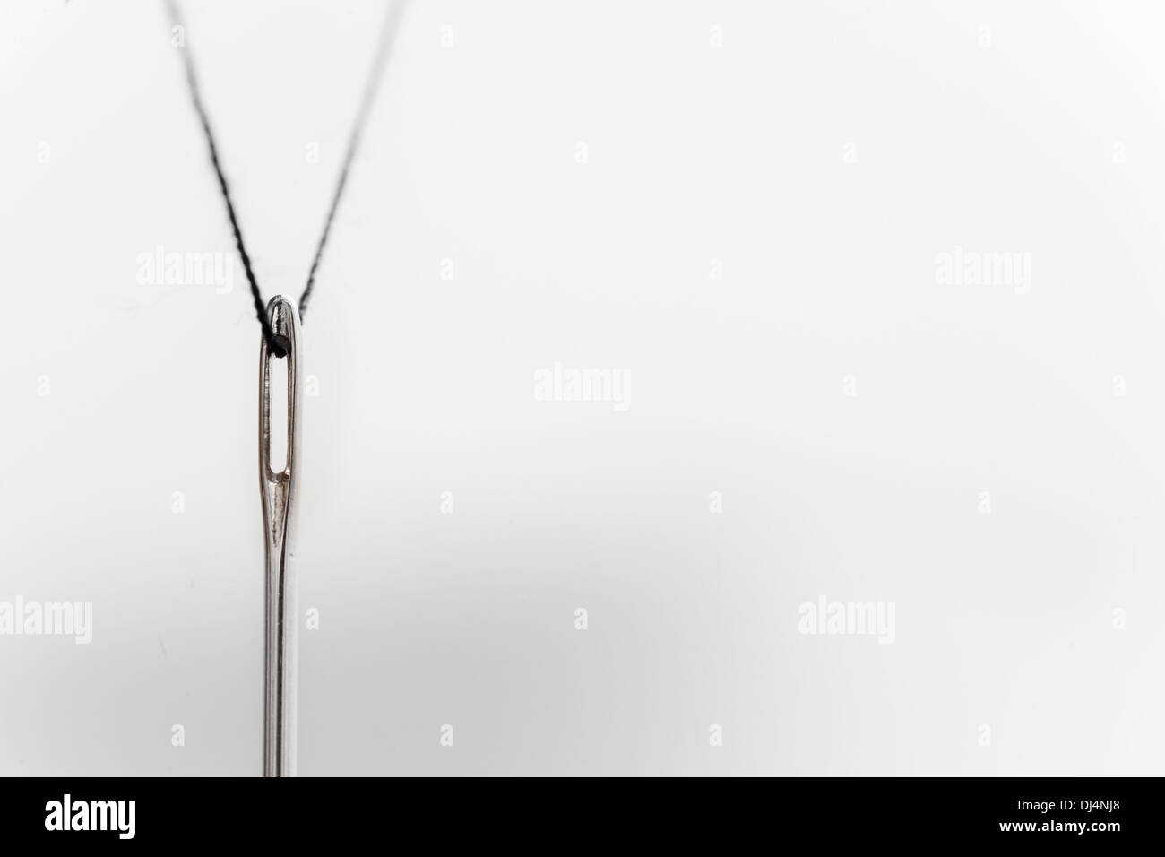 A steel needle hanging on a black thread on a white background Stock ...