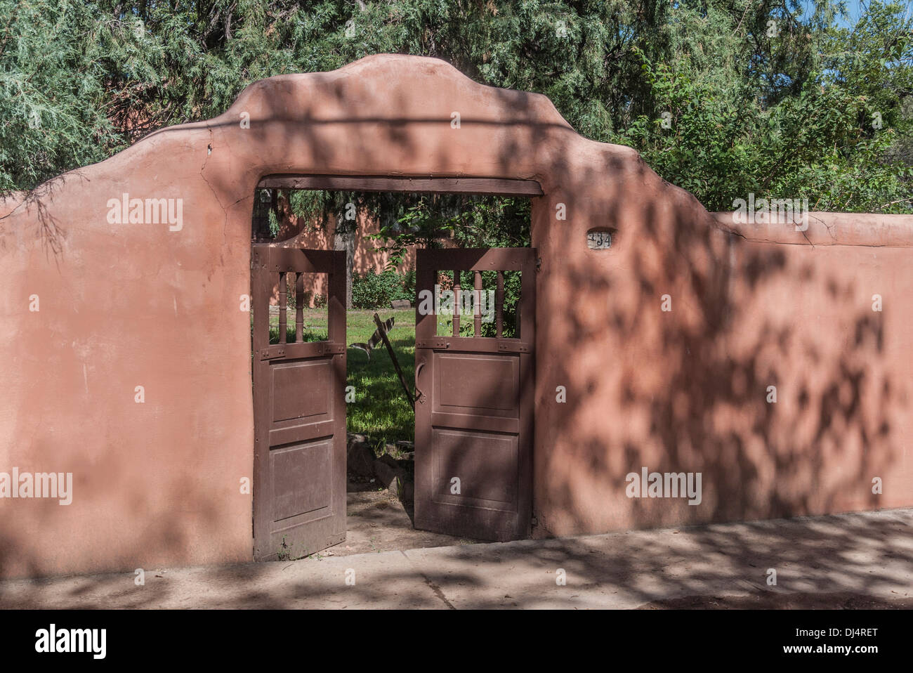Traditional wooden door on a stepped square arch adobe wall in dappled ...