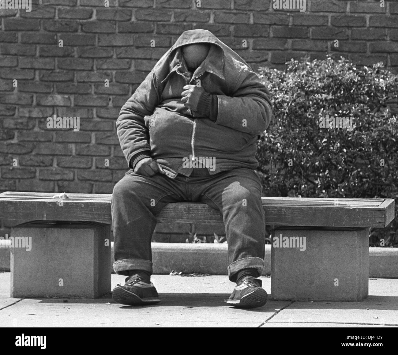 A homeless man sits on a bench hiding his face in Frederick Maryland ...