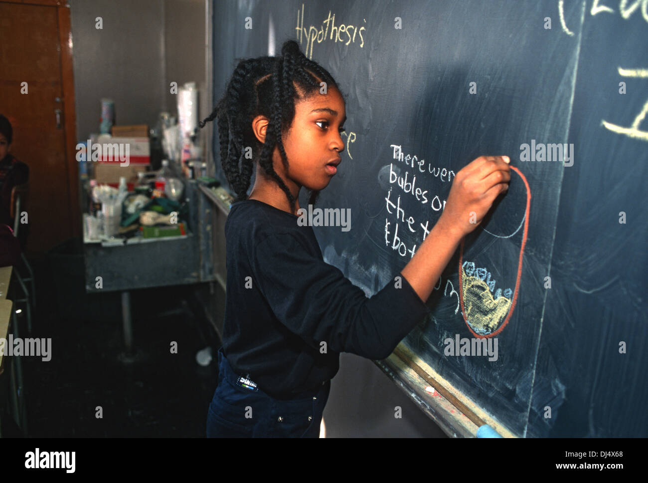 Elementary school student works at the chalkboard in science class ...
