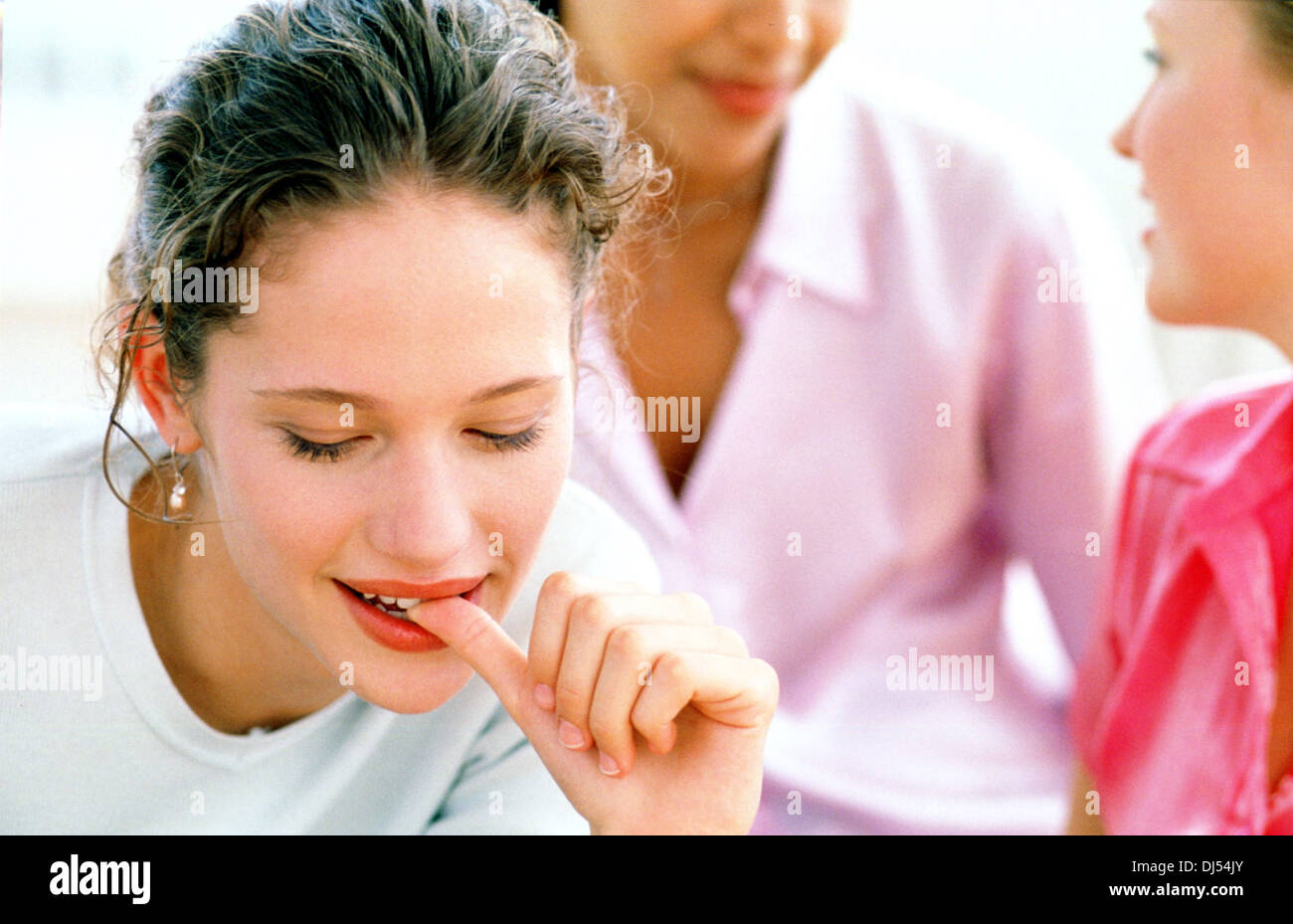Teenage girl biting her thumb while looking down Stock Photo - Alamy
