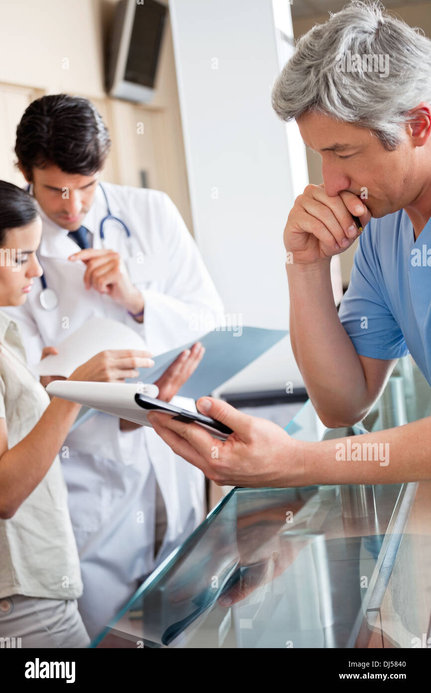 Doctor Reading Document At Reception Stock Photo - Alamy
