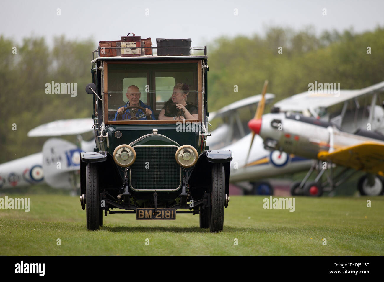 Vintage car drives along a line of aircraft at a Shuttleworth ...
