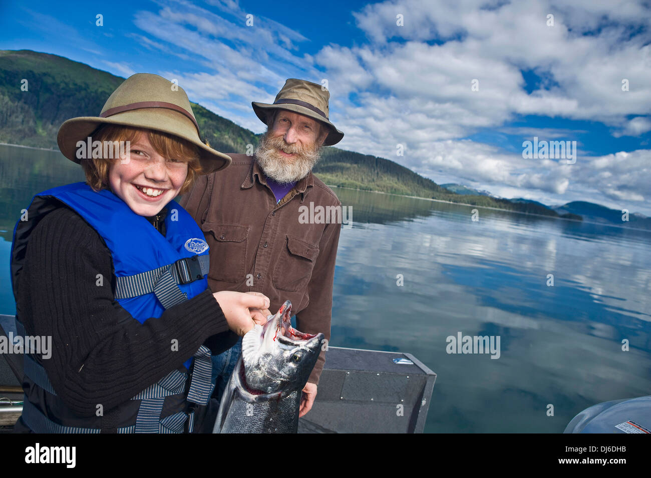 Teenage Boy And Grandfather Fishing For Silver Salmon From A Boat In ...