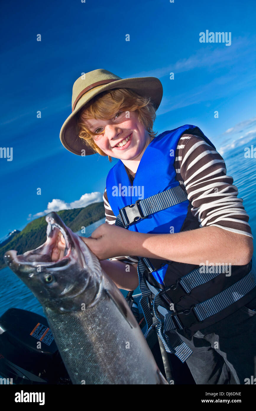 Teenage Boy Standing In A Boat Holding A Silver Salmon That He Caught ...