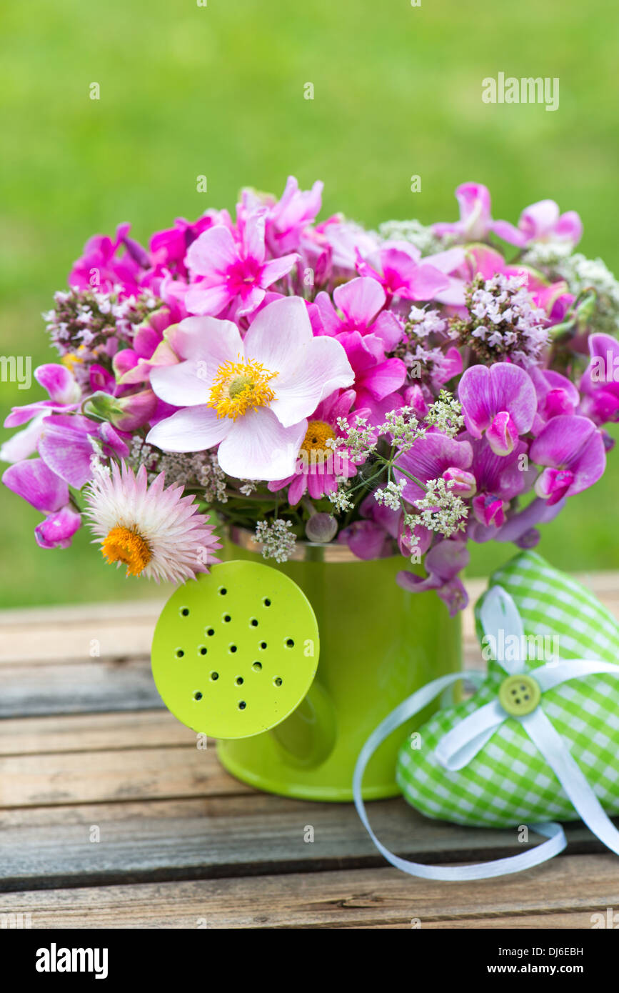 Pink garden flowers in a small watering can Stock Photo - Alamy